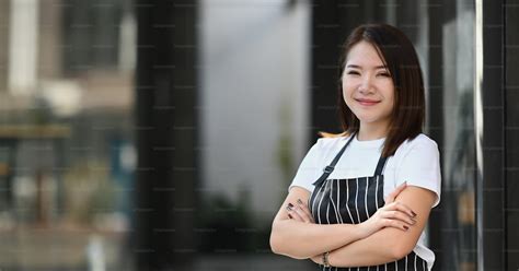 검은 앞치마를 입은 쾌활한 미소를 짓는 여성이 팔짱을 끼고 서서 카메라를 향해 웃고 있다 사진 Unsplash의 태국 이미지