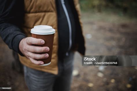 한 남자가 단풍을 배경으로 차 커피가 있는 테이크아웃 골판지 잔을 들고 있다 따뜻한 가을 분위기 부드러운 초점 복사 공간 10월에 대한 스톡 사진 및 기타 이미지 Istock