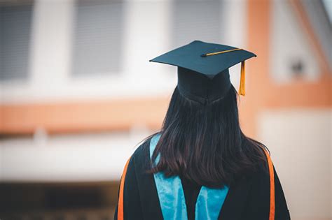 전통적인 가운 옷과 모자를 쓰고 일몰을 손에 들고 기장 졸업장을 들고 서 있는 졸업생 컨셉 교육 축하 졸업식 대학의 졸업생을 축하했다 25 29세에 대한 스톡 사진 및 기타