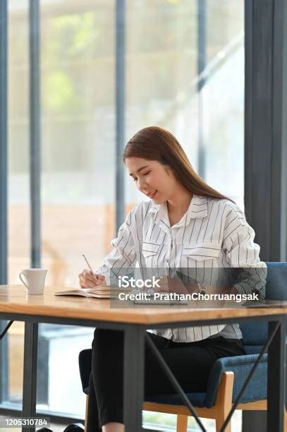 배경으로 편안한 거실현대 나무 작업 책상에 앉아있는 동안 줄무늬 셔츠 쓰기 복용 메모에 젊은 아름다운 여성의 사진 노트북에 대한 스톡 사진 및 기타 이미지 Istock