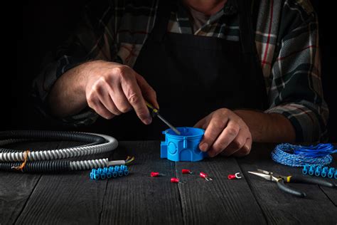 작업 중 마스터 전기 기술자의 손을 클로즈업합니다 파란색 정션 박스에 케이블 또는 와이어 설치 전기 장비의 설치 및 수리에 대한