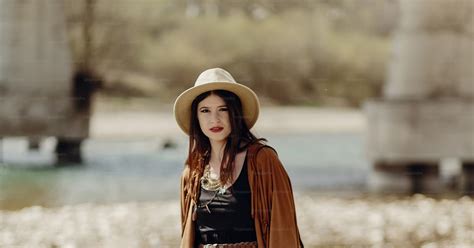 모자를 쓴 세련된 보헤미안 집시 여성 프린지 판초 부츠가 강 해변을 걷고 있습니다 힙 스터 여행자 소녀 모습 여름 여행 대기 순간 텍스트 공간 사진