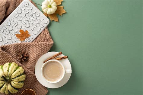 가을에서 영감을 받은 사무실 장면 키보드 갈색 니트 스웨터 뜨거운 커피 패티판 계피 스틱 나뭇잎 말린 오렌지 슬라이스 등을 녹색 배경으로 보여주는 최고의 모습 텍스트 또는