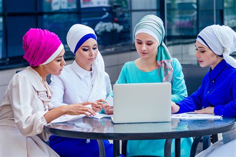 네 명의 백인 무슬림 사무실 숙녀 그룹이 사업가 파트너 취업 면접 숄과 터번과 함께 토론하면서 머리에 완벽한 피부와 메이크업을 노트북과 종이가있는 원탁에 앉아 있습니다 20