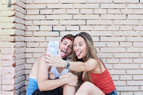 Couple Taking Selfies Against Brick Wall By Stocksy Contributor Ivan Gener Stocksy