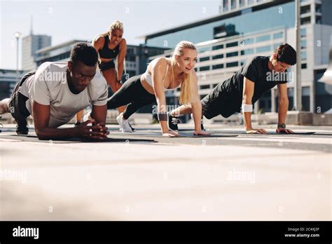 Group Of People Doing Core Exercise On Fitness Mat Outdoors Athletic
