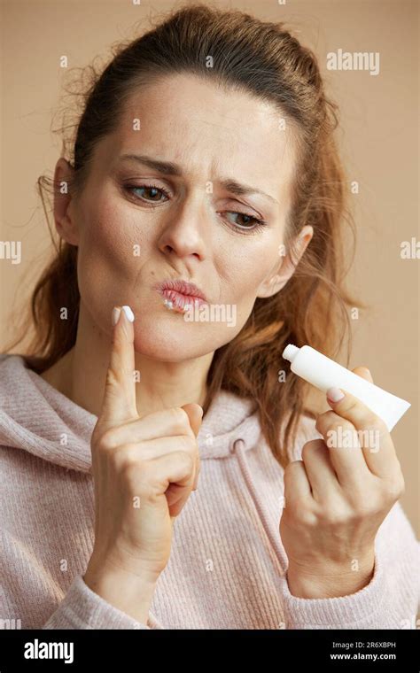 Female With Herpes On Lips And Ointment In A Tube Applying Ointment Using Finger Isolated On