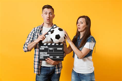 젊은 커플 여자 남자 축구 팬 지원 기운 흥분된 축구공 영화 Clapperboard 노란색 배경에 고립 된 만들기와 팀 스포츠 가족 레저 라이프 스타일 개념입니다 스튜디오