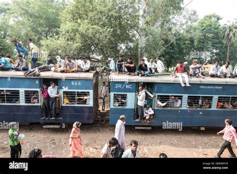 Passengers On Top Of Overcrowded Train At A Train Station In Rural