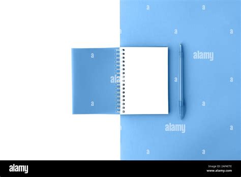 Top View Of Opened Trendy Blue Cover Spiral Notepad With Pen On Blue And White Background Flat