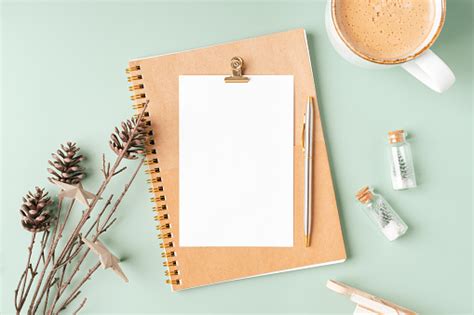 상단 보기 모형 빈 종이와 상단 보기 데스크톱 크리스마스 메모장 플래너 커피 한 잔 나무 브런치 크리스마스 에코 자연 장식 노트북 및 문구와 녹색 민트 테이블 배경에 플랫