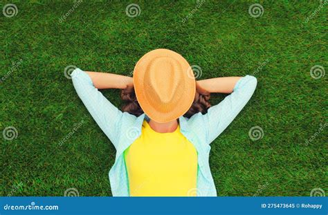 Happy Relaxing Girl With Straw Hat Covering Her Face Lies On Green Grass In Summer Park Top
