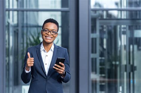 행복하고 성공적인 비즈니스 여성은 승리와 행복한 날에 기뻐하고 축하하며 아프리카 계 미국인 미소가 휴대 전화를 손에 들고 있습니다 25 29세에 대한 스톡 사진 및 기타