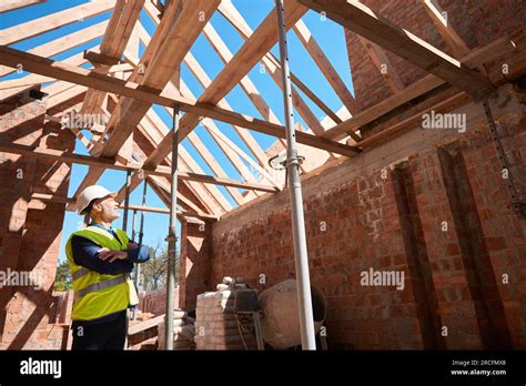 Male Constructor In Uniform Checking Walls Support And Roof Beams Of