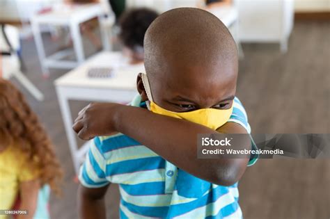 학교에서 입을 가리는 동안 얼굴 마스크 재채기를 입고있는 소년 팔꿈치 안쪽에 기침 또는 재채기에 대한 스톡 사진 및 기타 이미지