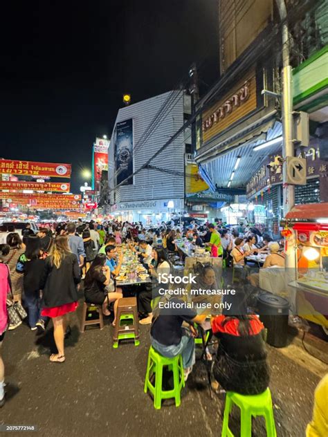 태국 방콕 차이나타운의 야간에 야외 식사를 하는 길거리 음식 시장의 이미지 길거리 음식 가판대 주변의 의자에 앉아 있는 사람들 빨간 거리 현수막 전경에 초점 건물 외관에