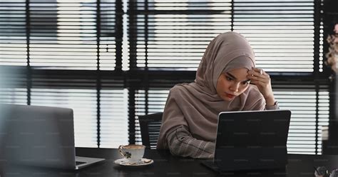 히잡을 쓴 사려 깊거나 스트레스가 많은 이슬람 소녀는 사무실 책상 위의 태블릿 컴퓨터 앞에서 직장에서 화가 난다 사진 Unsplash의 태국 이미지