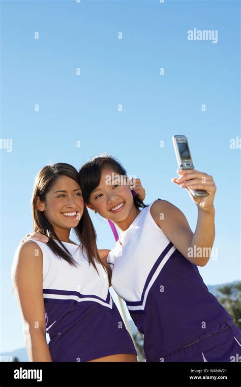 Two Cheerleaders Taking Photo Of Themselves With Camera Phone Stock