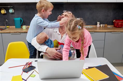 검역 및 폐교 중에 집에서 일하는 팔에 신생아와 아버지 코로나 바이러스 발생 젊은 사업가 프리랜서는 아이들과 함께 노트북에서 놀고 있습니다 부모에 대한 스톡 사진 및 기타