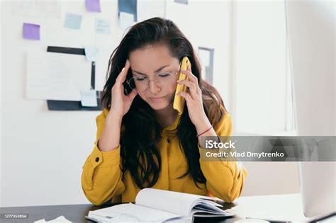 피곤 한 화가 젊은 프리랜서 여자 또는 그녀의 전화로 이야기 하는 사무실 노동자 그녀의 얼굴은 그녀의 손에 떨어졌다 그녀는 노트북을 본다 여자는 노란색 블라우스와 둥근