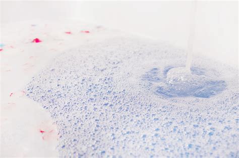 거품 새로운 세라믹 욕실 웰빙을 위한 목욕 장미 꽃잎과 푸른 물 꽃 꽃잎과 아로마 테라피 목욕을 하십시오 흰 거품이 있는 물 장미 욕실에 떠 물 흐름 가꿔주기에 대한 스톡