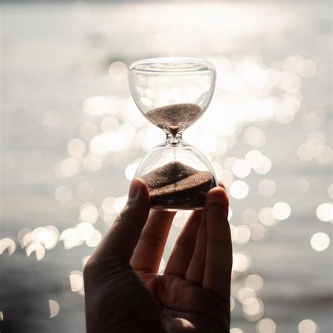 Premium Photo Hand Holding A Hourglass With Sea