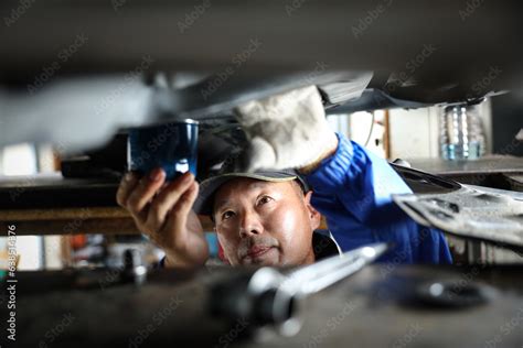 Stockfoto 동네 카센터에서 리프트에 올려진 자동차 하체를 점검하는 엔지니어의 클로즈업 Adobe Stock