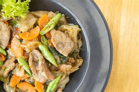 在左侧框架中使用自然光在顶部视图中翻炒面和猪肉胡萝卜Yardlong豆和生菜和黑酱油高清图片下载 正版图片506646361 摄图网