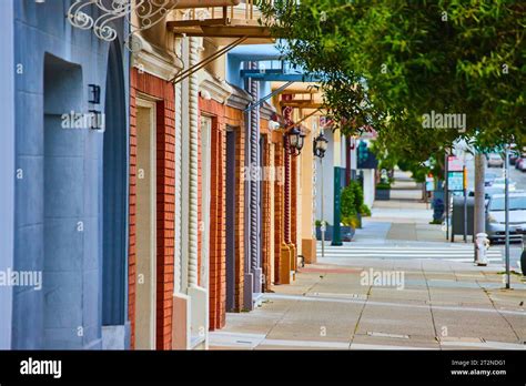 Tree Overhanging Wide Sidewalk Tunnel View With Vibrant And Colorful Brick Entrances To