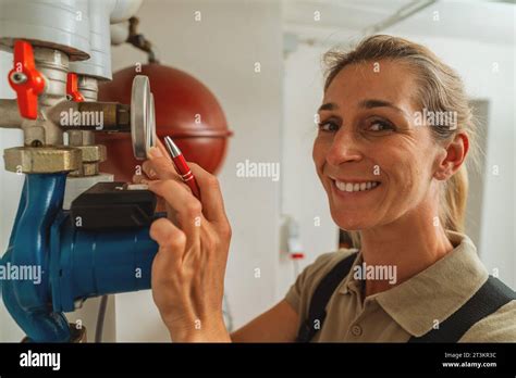 Happy Female Heating Engineer Checks Gas Thermostat At A Boiler Room With A Old Gas Heating