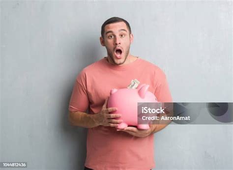 놀라운 얼굴 두려워 하 고 공포 식으로 흥분 충격에서 무서 워 저금통을 들고 회색 그런 지 벽에 젊은 백인 남자 남자에 대한