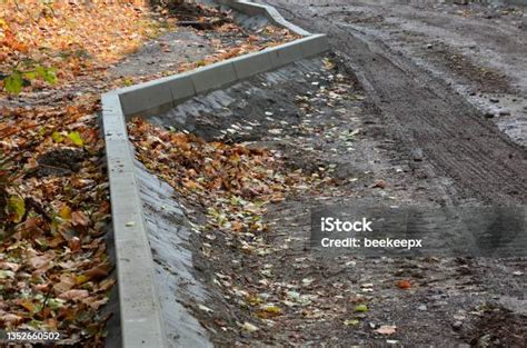 포장 구조 기초에 콘크리트 연석을 누워 건설 작업 굴삭기 빌더는 새로운 거리 표면을 만들고있다 타일은 자갈에 놓입니다 가을 작업 공간 스쿱 바퀴 전등에 대한 스톡 사진 및