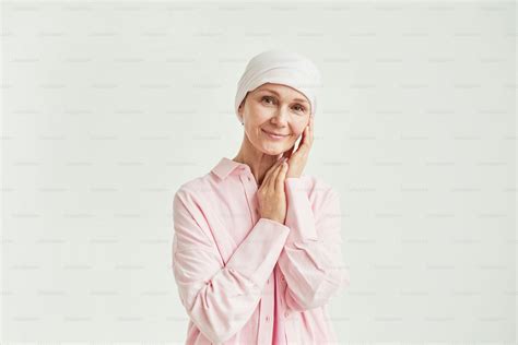 머리 스카프를 두르고 카메라를 바라보는 우아한 성숙한 여성의 미니멀한 초상화는 유방암 회복을 축하하는 흰색에 기대어 서 있다 사진 Unsplash의 사업 이미지