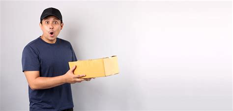 스튜디오의 흰색 배경 위에 고립 된 소포 우편함이 서있는 검은 모자를 쓴 행복한 젊은 배달 아시아 남자의 이미지 검은색에 대한 스톡 사진 및 기타 이미지 Istock