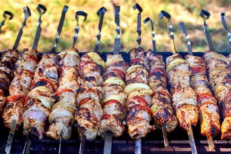 숯 위에 바비큐 그릴을 준비한 다진 토마토와 양파 조각으로 꼬치에 매달린 육즙이 많은 돼지 고기 조각 Shashlik 또는 Shish 케밥은 동유럽에서 인기가 있습니다