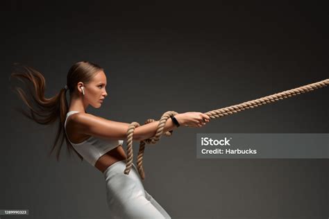 회색 배경에 고립 된 밧줄을 당기는 흰색 스포츠웨어에서 스포티 한 매력적인 여성의 측면 보기 20 24세에 대한 스톡 사진 및 기타 이미지 Istock