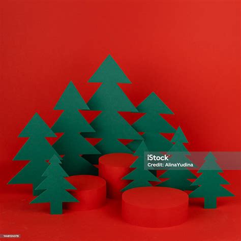 밝은 빨간색 새해 배경에는 세 개의 빨간색 실린더 연단 모형 녹색 종이 가문비나무가 프레젠테이션 화장품 선물 복사 공간 사각형을 위한 숲으로 있습니다 광고 디자인을 위한