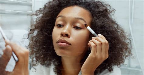 뷰티 메이크업 화장실에서 거울 앞에서 브러시로 눈 피부에 화장품을 바르는 여자 하얀 목욕 가운을 입은 아프리카 소녀의 초상화가 아침에 화장을 하고 있다 사진