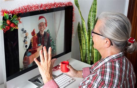 크리스마스 인사말을 위해 화상 통화를 하는 두 명의 선배 수염과 산타 모자를 들고 선물남자 커피를 마시며 손으로 흰 머리를 한 여성 20에 대한 스톡 사진 및 기타 이미지