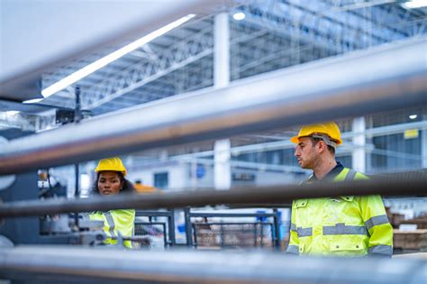 남성과 여성 기술공 엔지니어는 무거운 기계에 과정을 검사합니다 기계 공학 팀 생산 산업 제조 태블릿과 폴드를 들고 있는 작업자