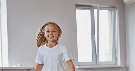 회색 소파 앞에 서 있는 동안 실내에서 즐거운 시간을 보내는 행복한 미소를 짓는 작은 여자 아이의 전체 길이 초상화 사진 Unsplash의 실내 이미지