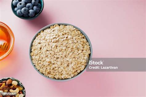 분홍색 배경에 귀리 플레이크 블루 베리 견과류와 꿀 드라이 오트밀과 식이 아침 식사 재료 건강한 아침 식사 개념 공간을 복사합니다 위쪽 보기 귀리 가루에 대한 스톡 사진 및