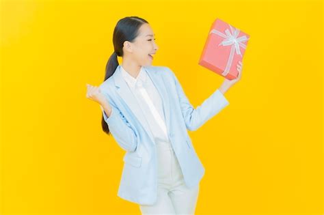 노란색에 빨간 선물 상자와 함께 초상화 아름 다운 젊은 아시아 여자 미소 무료 사진