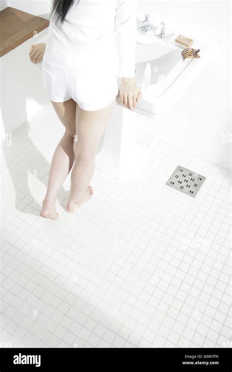 Low Section View Of A Woman Standing In Front Of A Bathroom Sink Stock