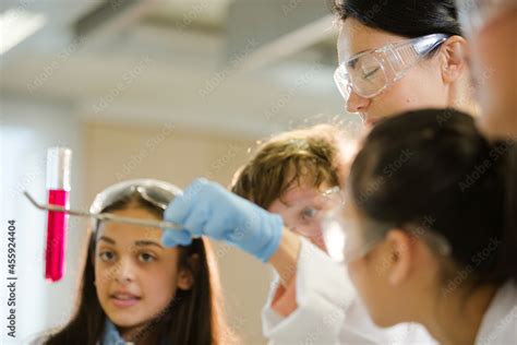 Female Teacher And Babes Examining Liquid In Test Tube Conducting Scientific Experiment In