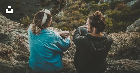 절벽에 앉아있는 두 여자가 푸른 수역을 보며 이야기를 나누고 있습니다 사진 Unsplash의 무료 아빌라 비치 이미지