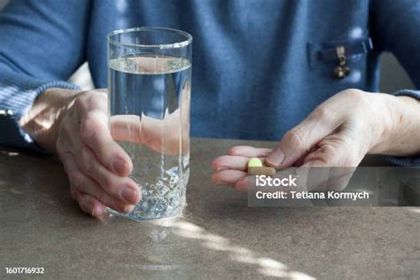 알약과 식수 한 잔을 들고 있는 나이든 여성의 클로즈업 노인 여성은 질병에 대한 약을 복용 할 것입니다 노년기의 건강 문제 특정 약물 복용 약 남자에 대한 스톡 사진 및