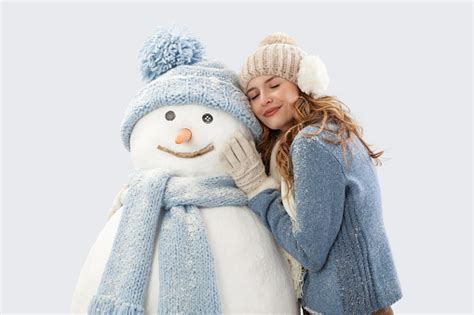 따뜻한 겨울 옷 모자 스카프를 뜨개질한 눈사람을 껴안고 있는 행복한 젊은 여자 겨울 시즌의 크리스마스 휴가 기간 동안 스키 여행 냉각 및 가열 온도 개념 냉동된에 대한 스톡