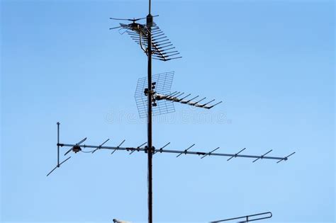 Communication Antennas Atop A Tower Against A Clear Blue Sky During
