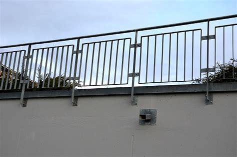 수직 울타리 기둥이 4 개의 콘크리트 나사로 땅에 고정 된 다리 난간 난간은 다리 측면에서 콘크리트로 고정됩니다 거터 튜브 파이프 하수 처리 0명에 대한 스톡 사진 및 기타